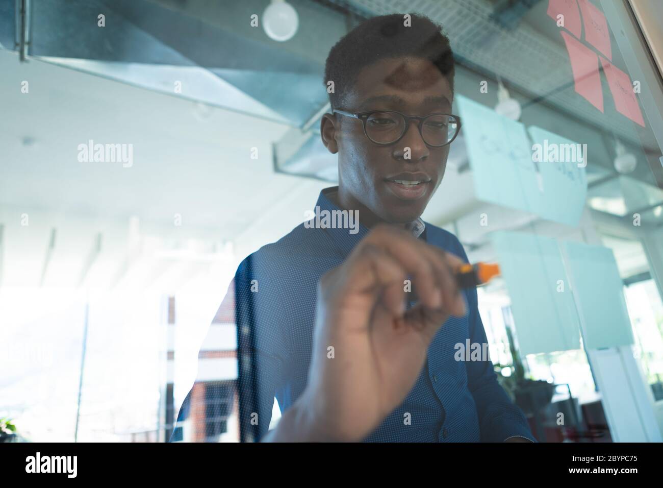 African American man writing on transparent board in an office Stock ...