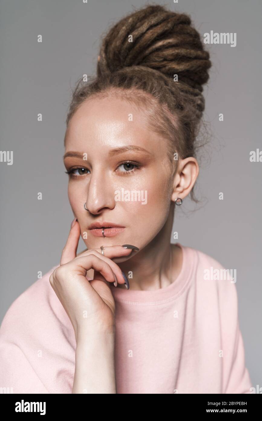 Portrait of an attractive young woman with dreadlocks standing isolated ...