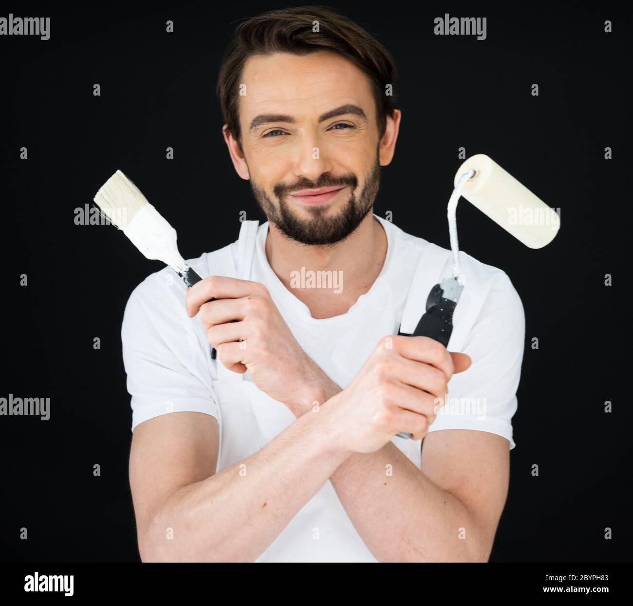 Smiling painter holding a roller and brush Stock Photo - Alamy
