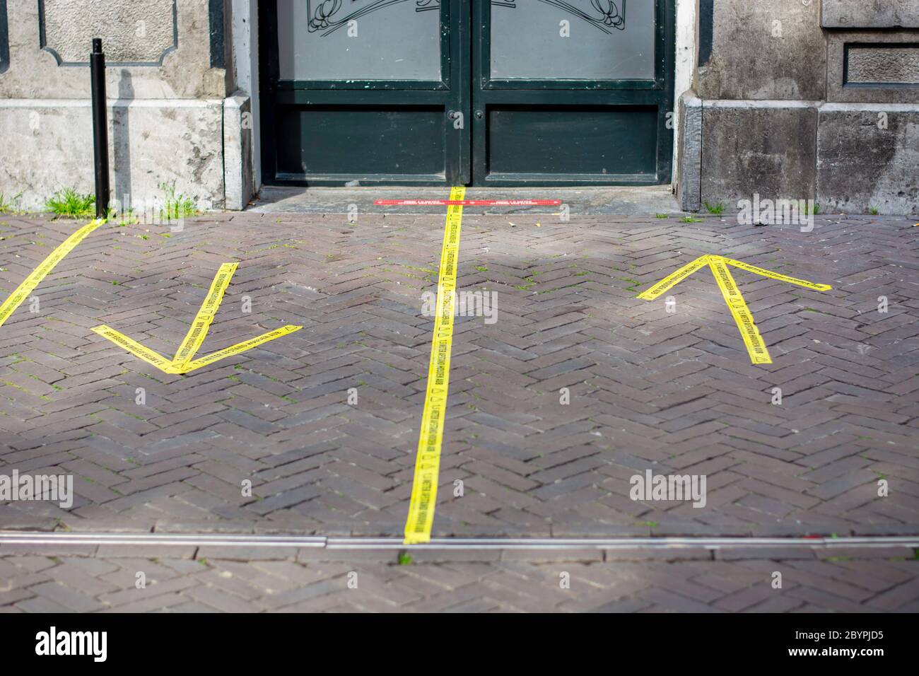 Entrance to a pub with yellow sticker tape reminding people in Dutch to ...