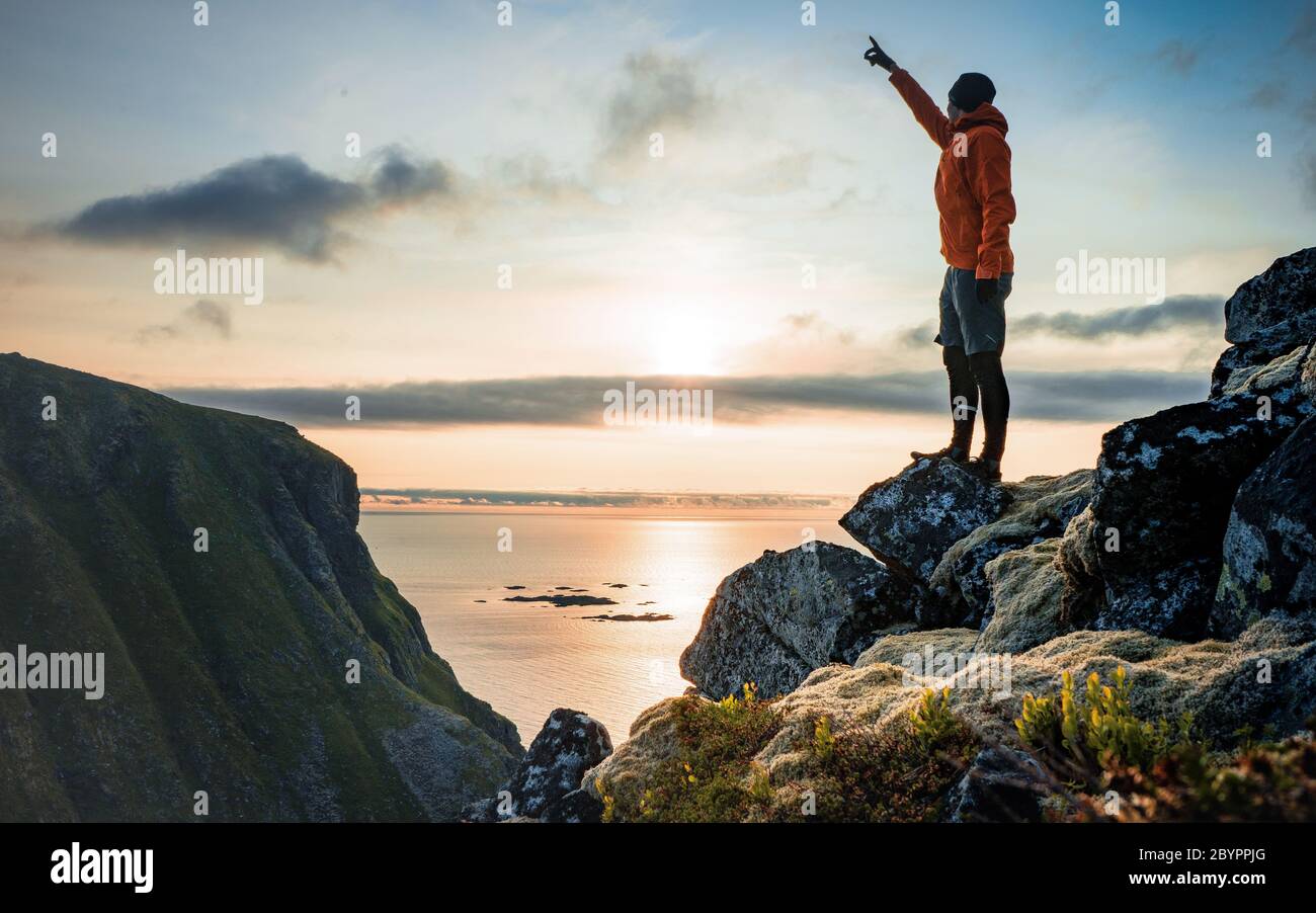Tourist stand alone on a rock and watching sea horizon within sunset ...
