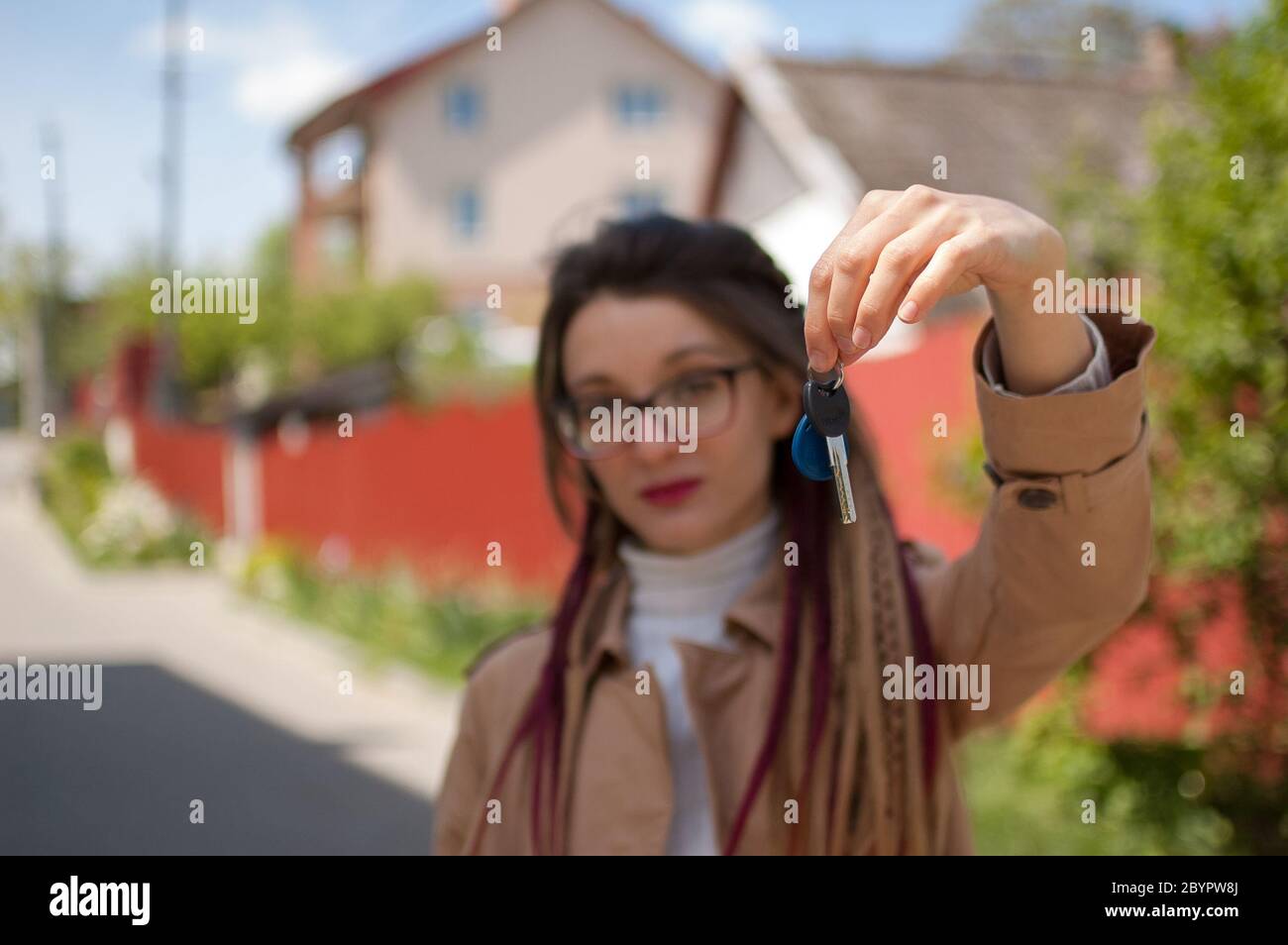 Modern young girl with long dreadlocks and eyeglasses is showing bunch ...