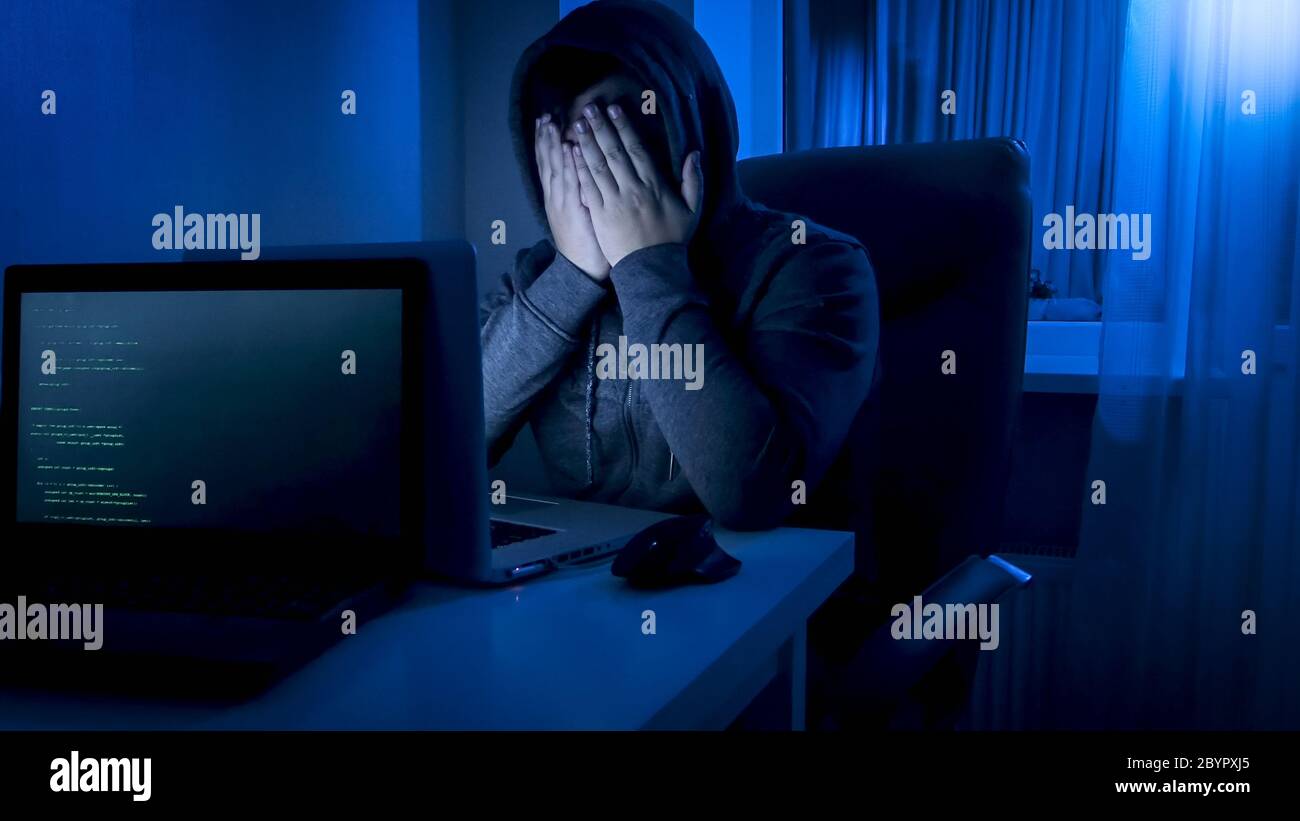 Stressed male programmer holding hands on his face while working on ...