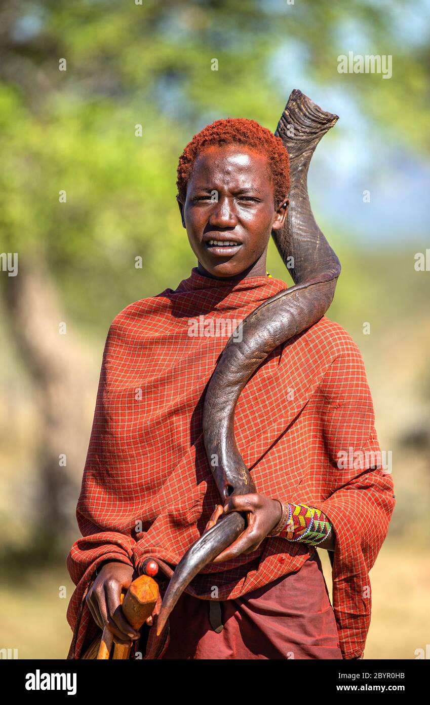 Young Masai warrior is standing in the savannah in traditional clothes ...