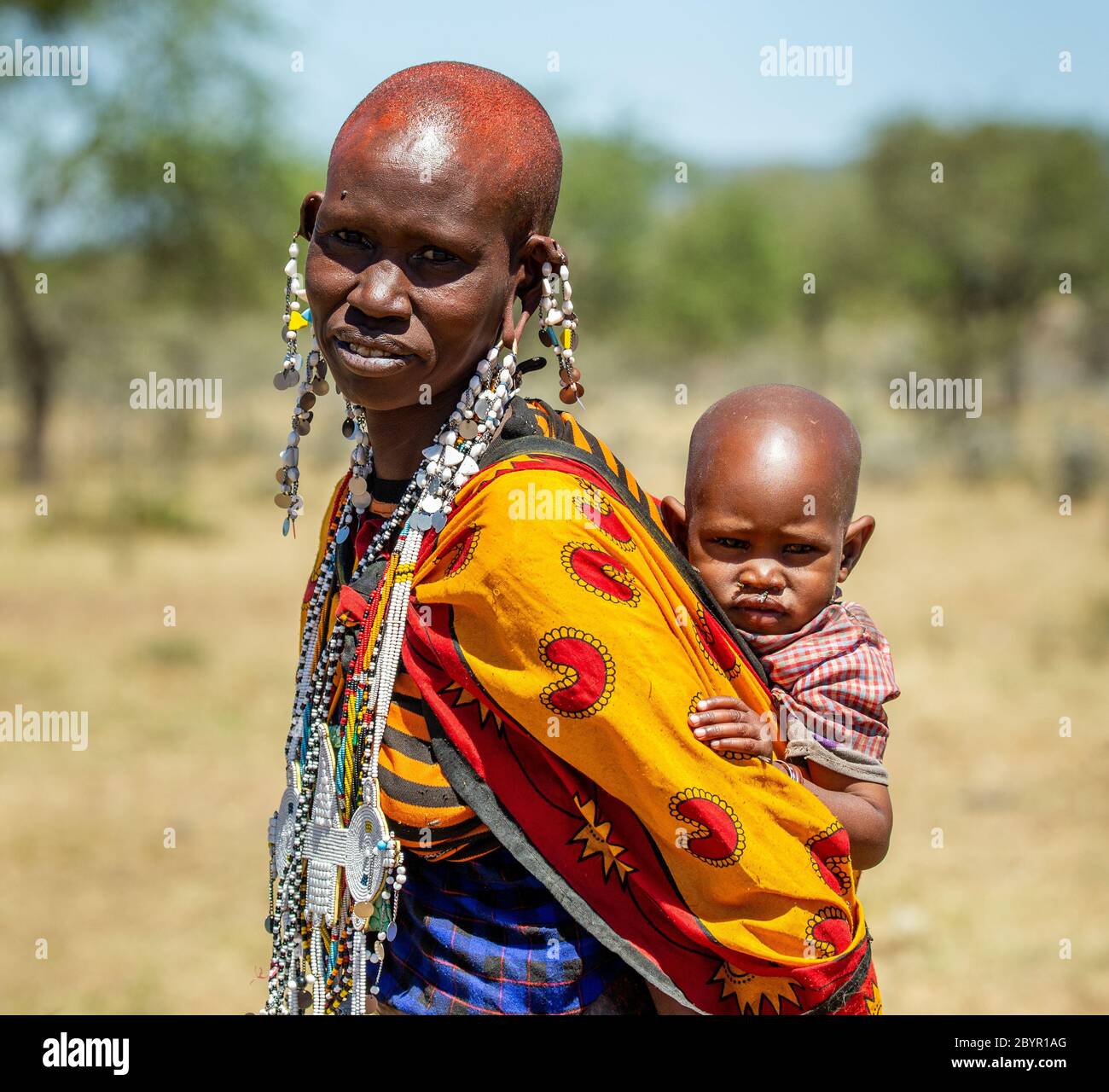 Portrait of a Masai woman with a child in traditional clothing in the ...