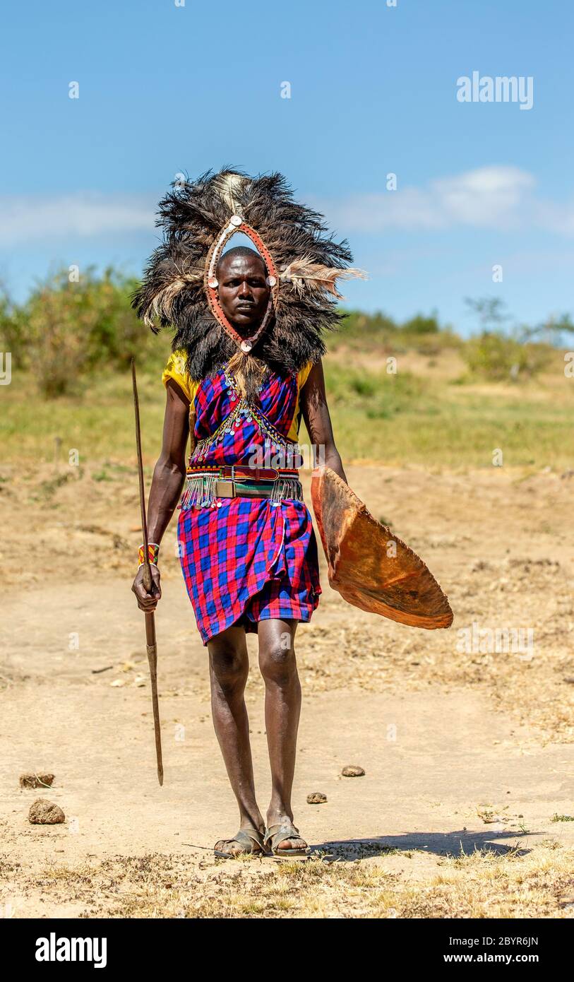 Masai warrior is standing in traditional clothing in a warrior's ...