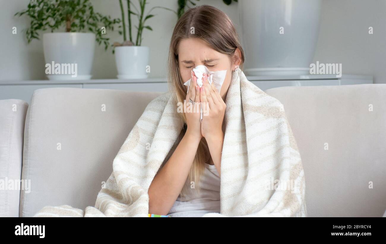 Portrait of sick woman with runny nose blowing nose in paper tissue ...