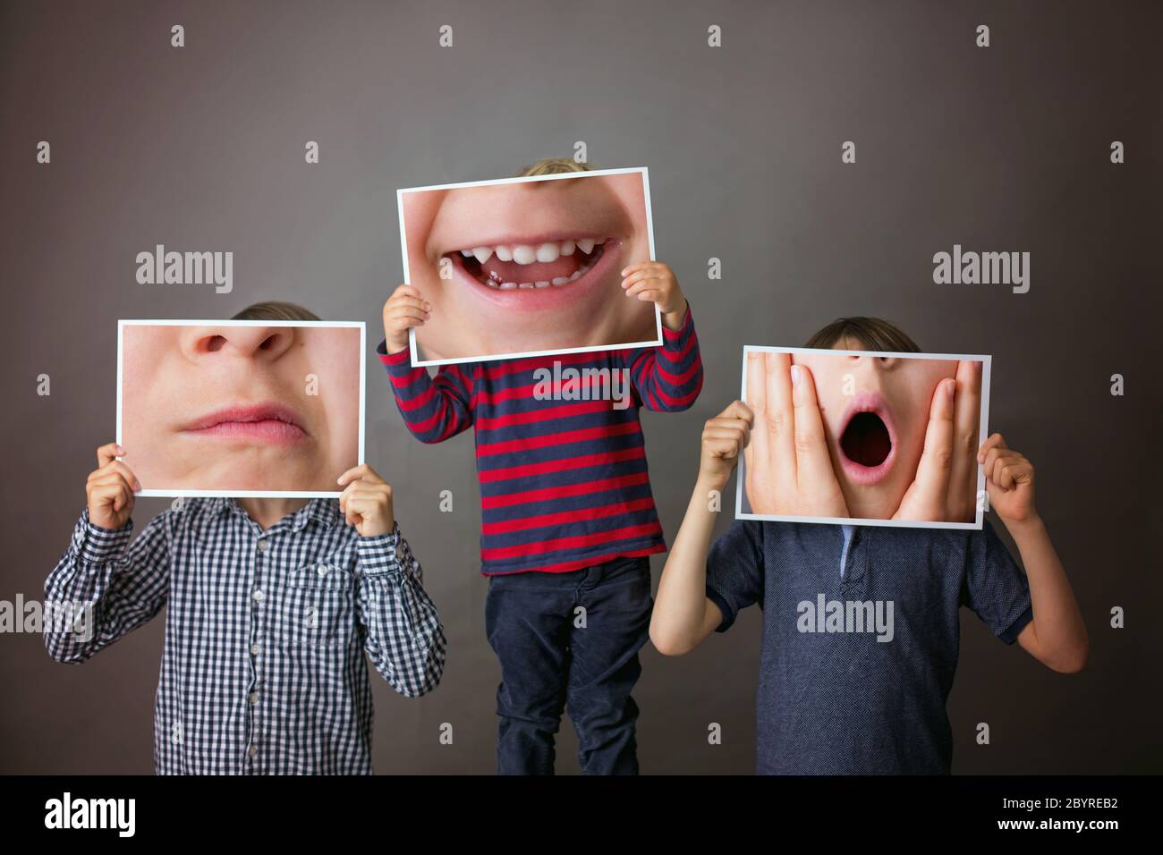 Three children, boy brothers, showing different emotions, hiding paper ...