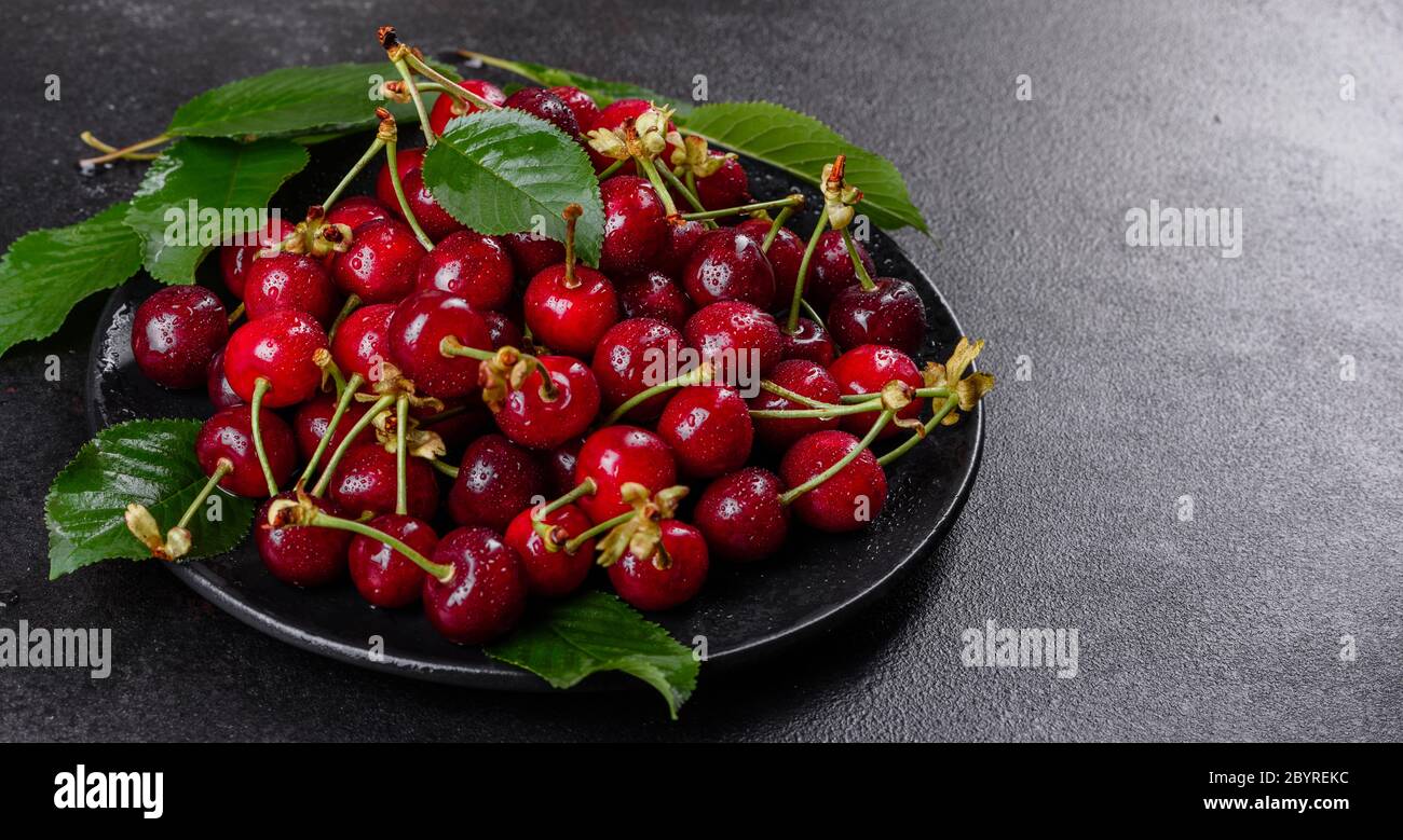 Close up of pile of ripe cherries with stalks and leaves. Large ...