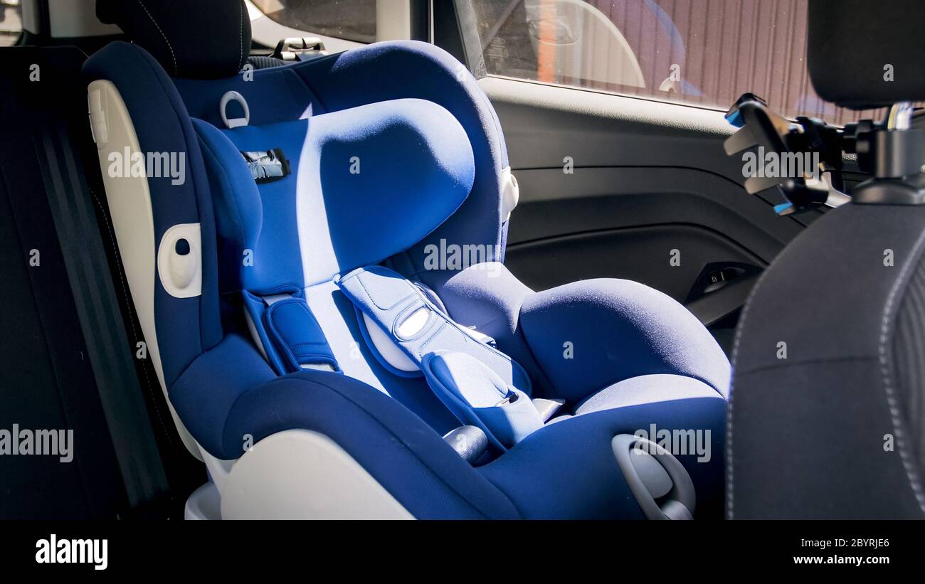 Empty blue baby car safety seat on car back seat at bright sunny day ...