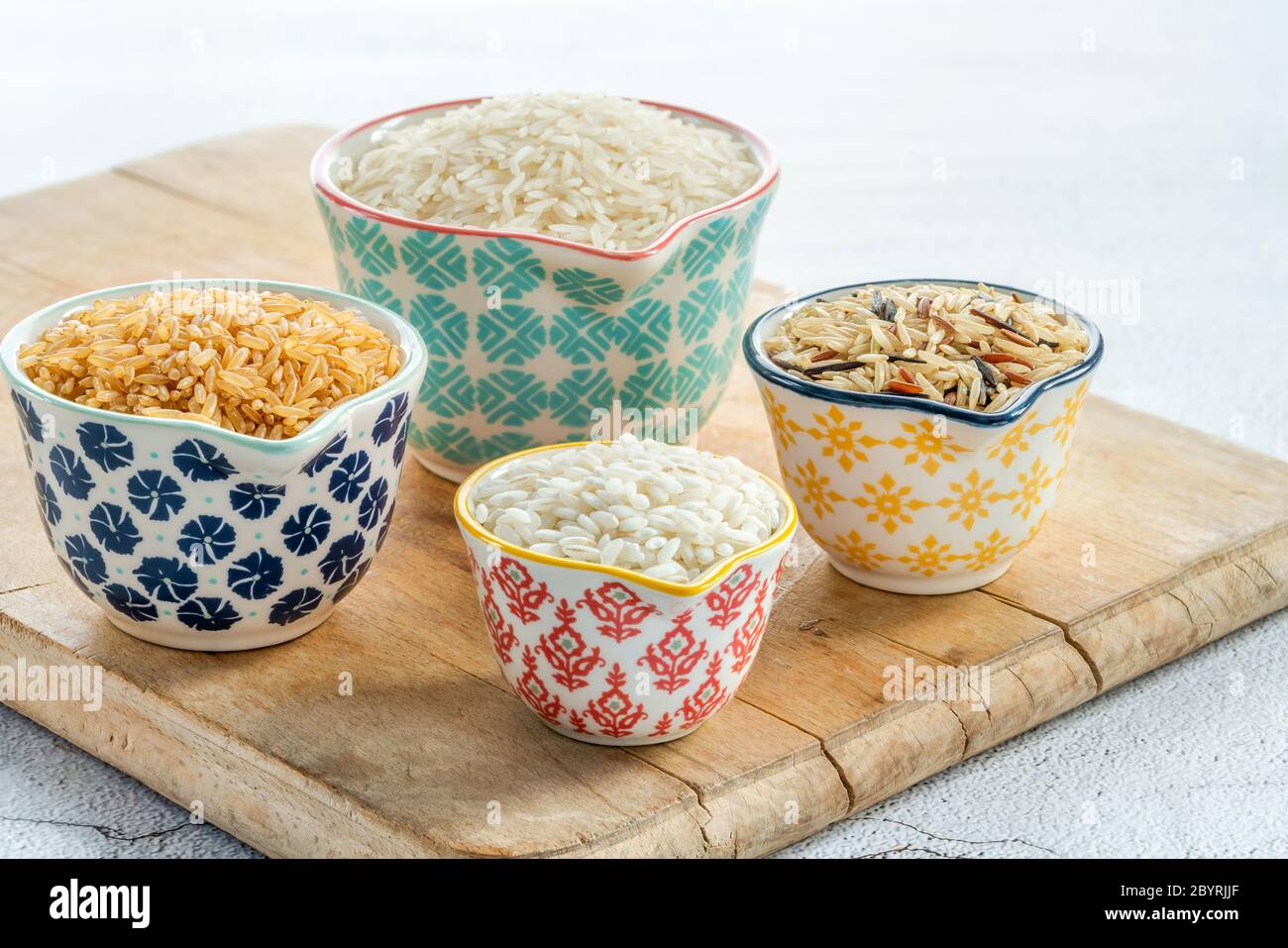Assortment of dry rice in ceramic pots on wooden board Stock Photo - Alamy
