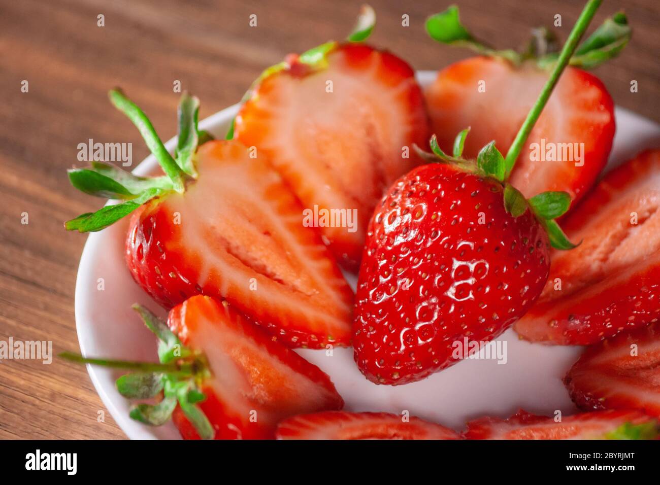 organic red strawberry on right side with cut strawberries on the left ...