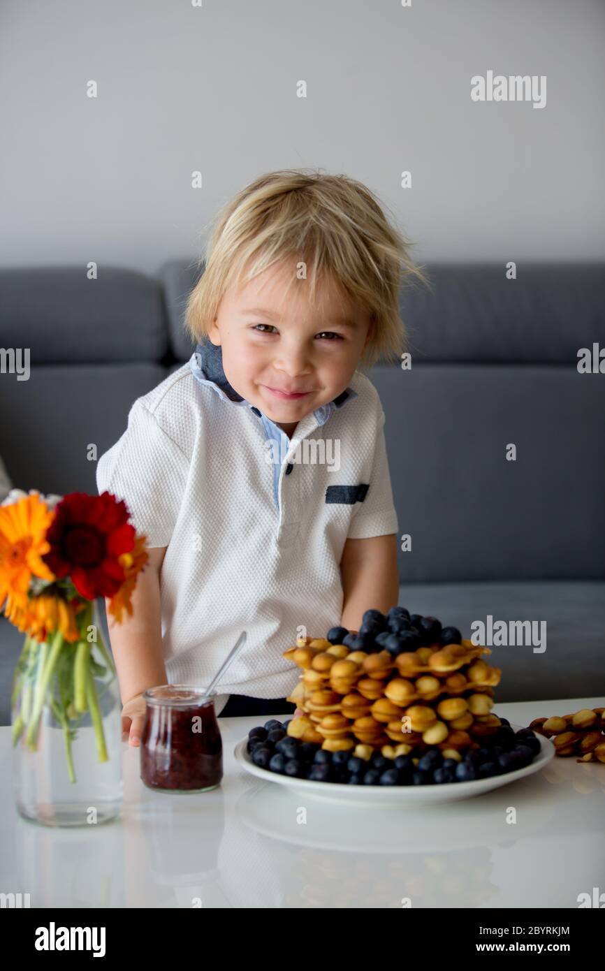 Sweet toddler child, boy, eating bubble waffles with fruits at home for ...