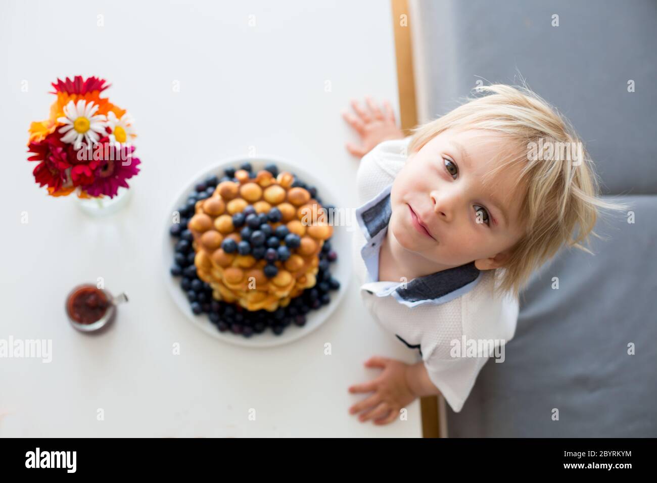 Sweet toddler child, boy, eating bubble waffles with fruits at home for ...