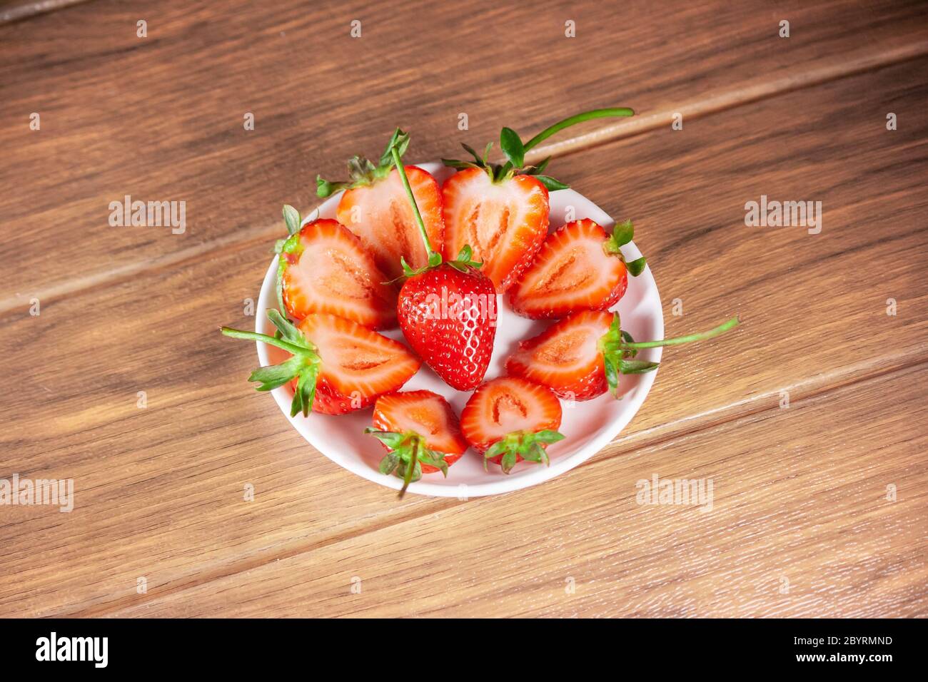 fresh red strawberry in the middle of the white porcelain plate with ...