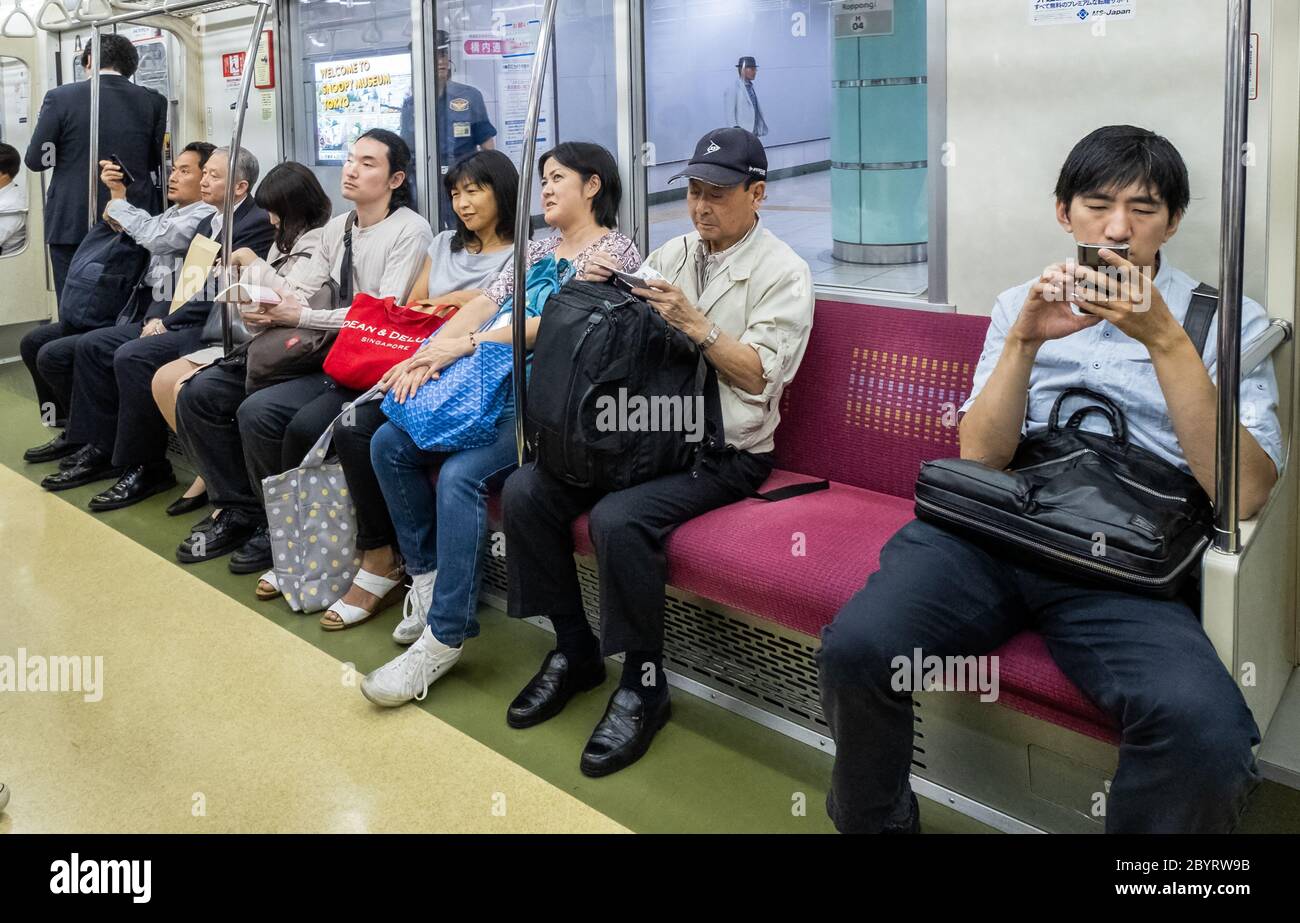 Commuters commuting in a Tokyo Metro Oedo line underground subway train ...