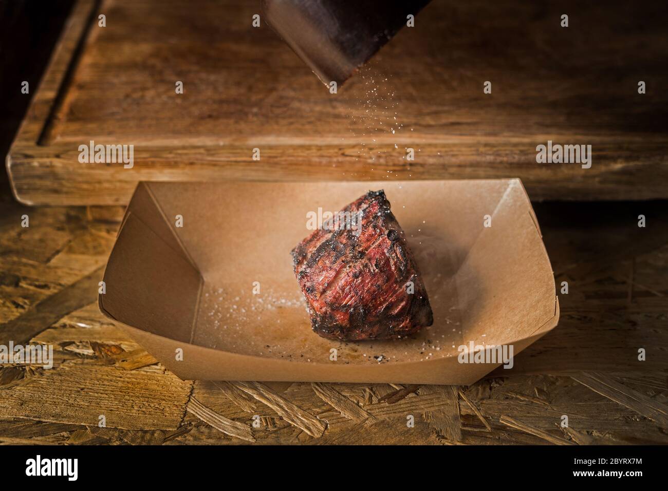 Closeup shot of delicious roasted beef meat in craft paper container on ...