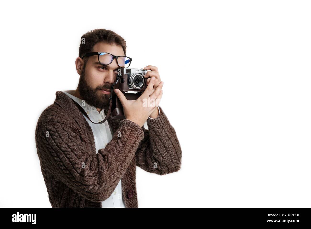 Confident hipster photographer with camera on a strap posing isolated ...
