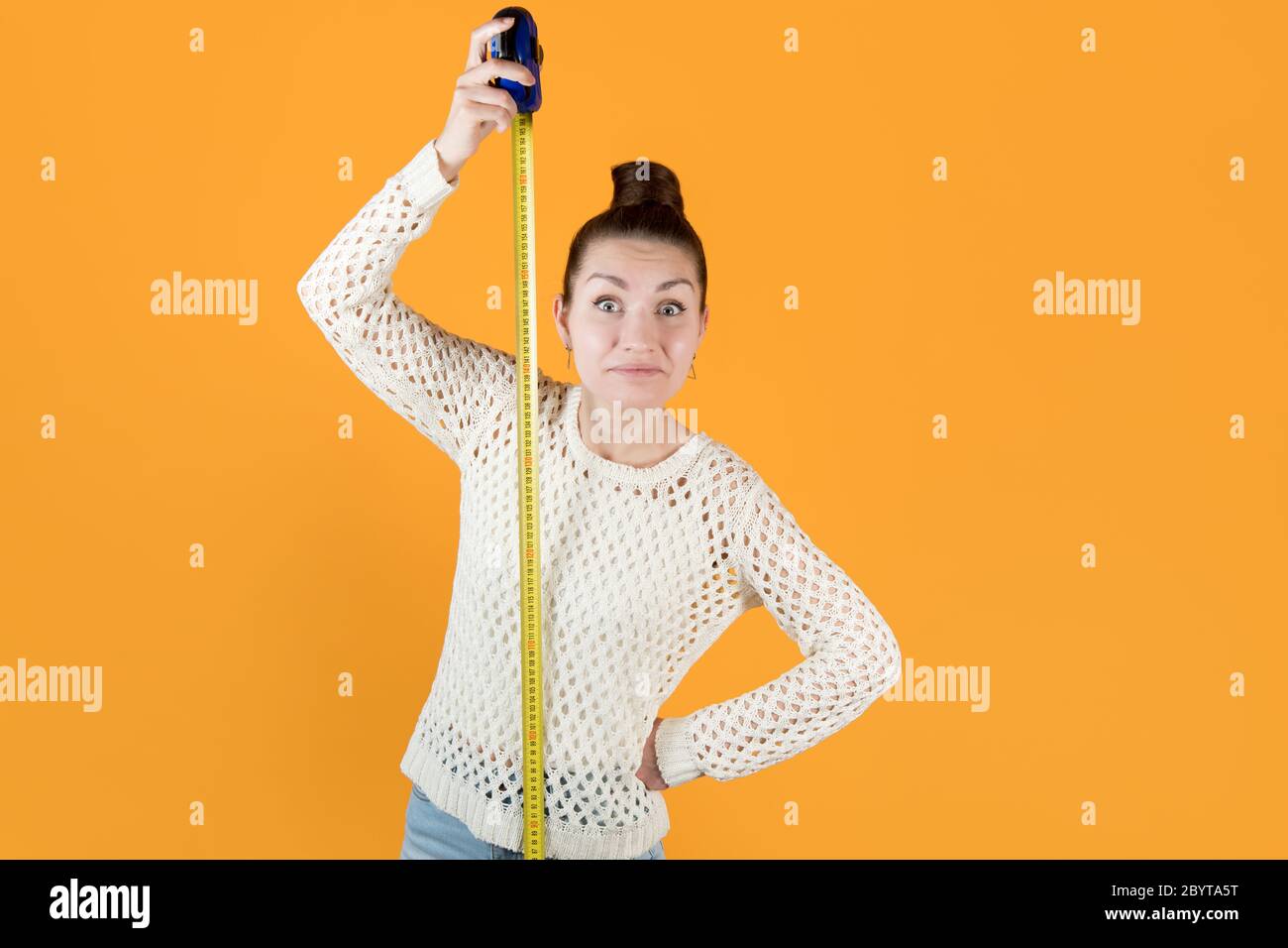 surprised smiling girl stands next to a stretched measuring tape Stock ...