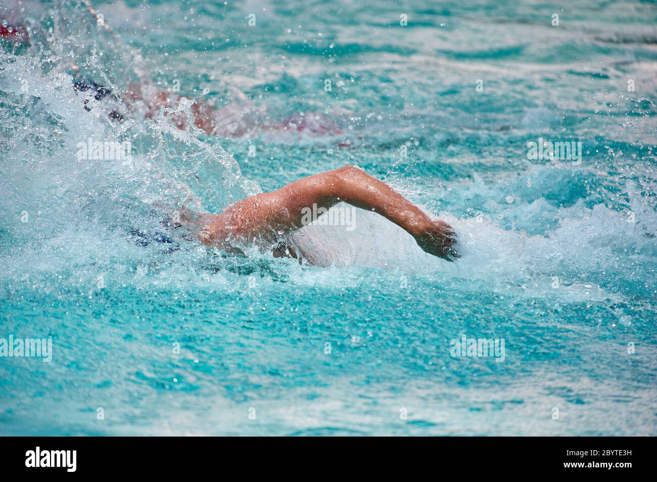 Athlete training swimming in olympic pool at gym blue water splashing ...