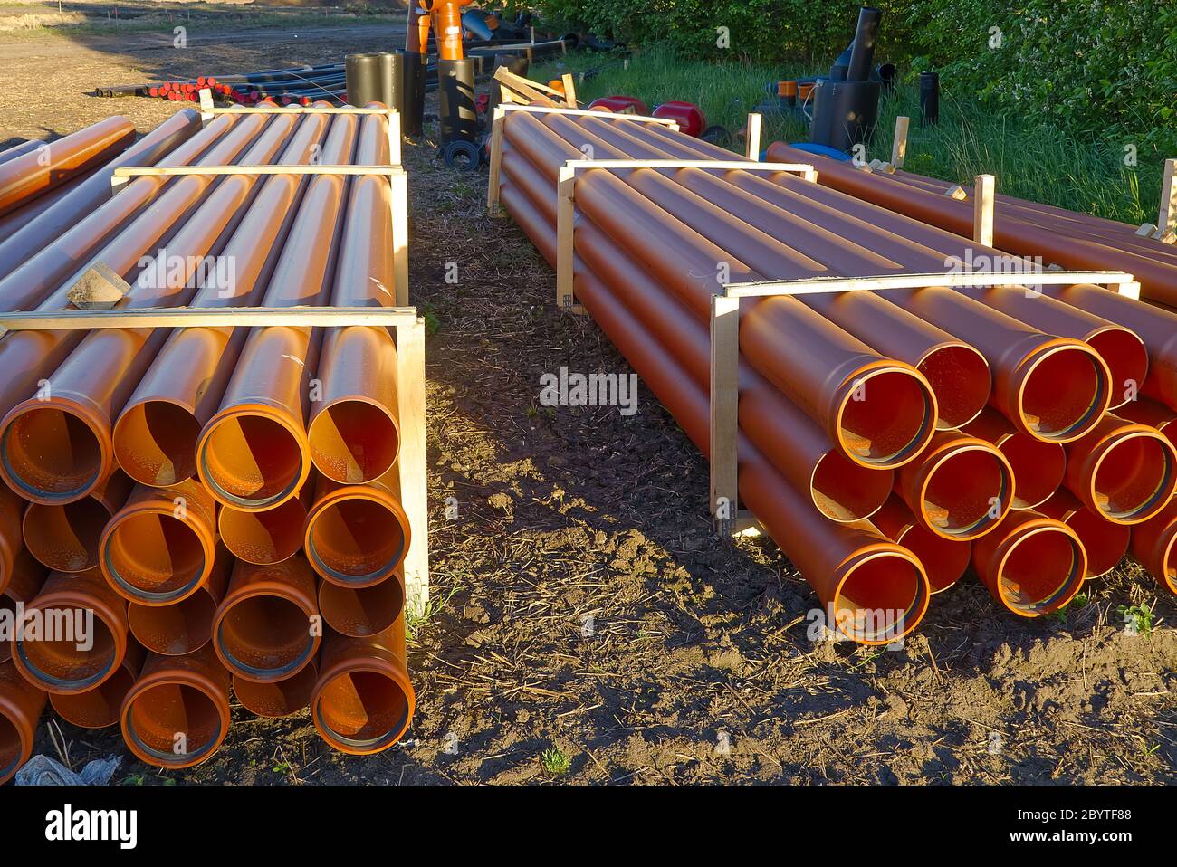 orange sewer pipes at a construction site. Underground orange plastic pipes. Stacked PVC orange ...