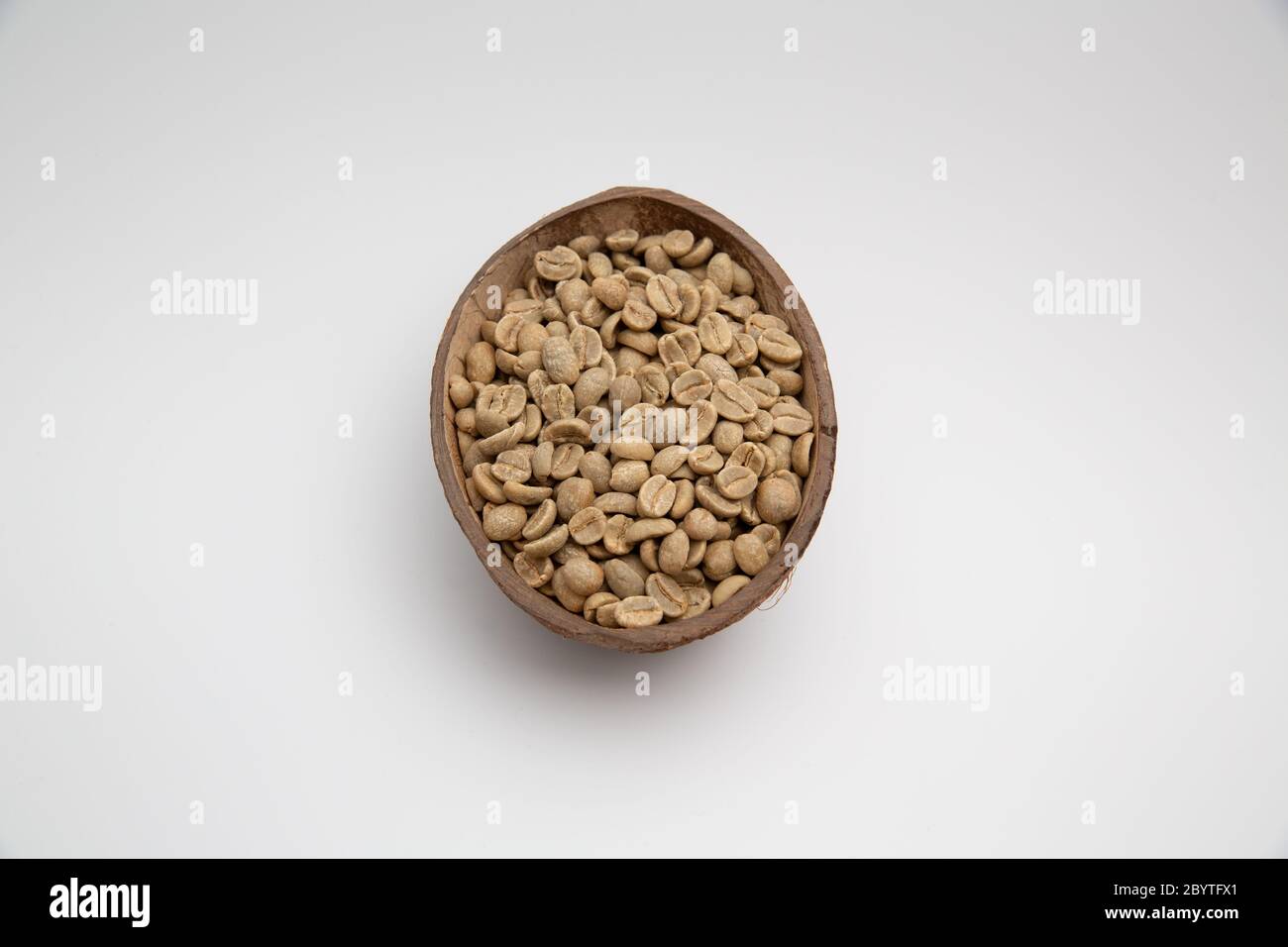 Close up shot of raw coffee beans in a coconut shell bowl isolated on ...
