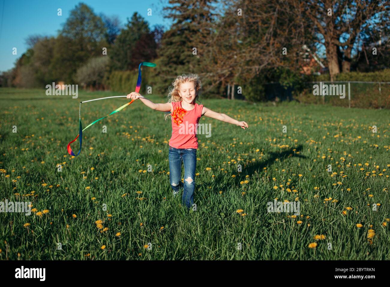 Happy child girl playing with ribbons in park. Cute adorable kid ...