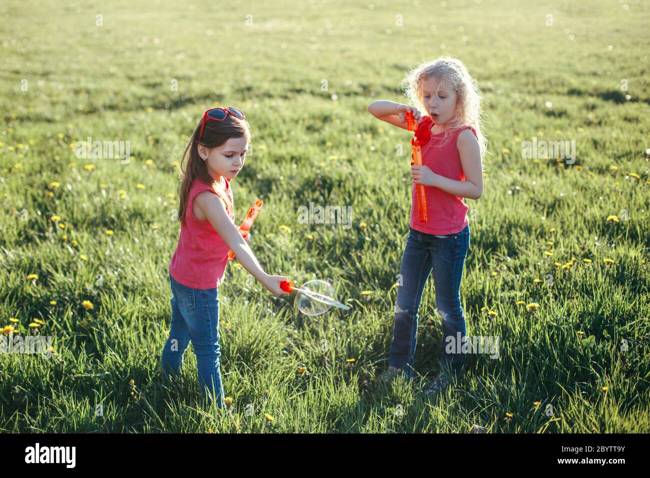 Catch a bubble. Girls friends blowing soap bubbles in park on summer ...