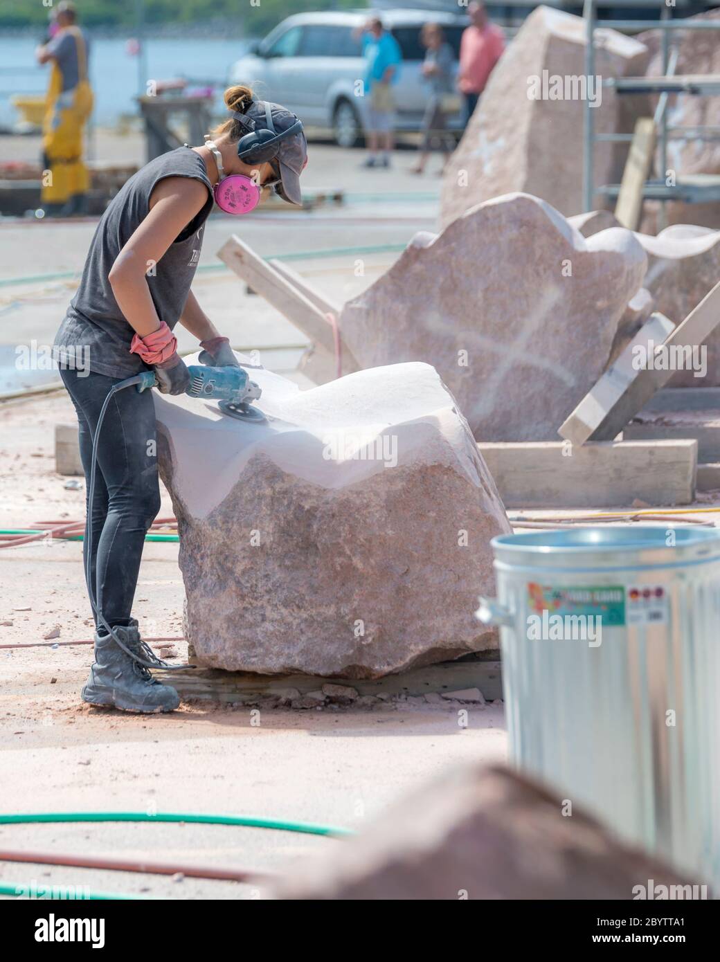 An artist works on a large block of stone at Sculpture Saint John, a ...
