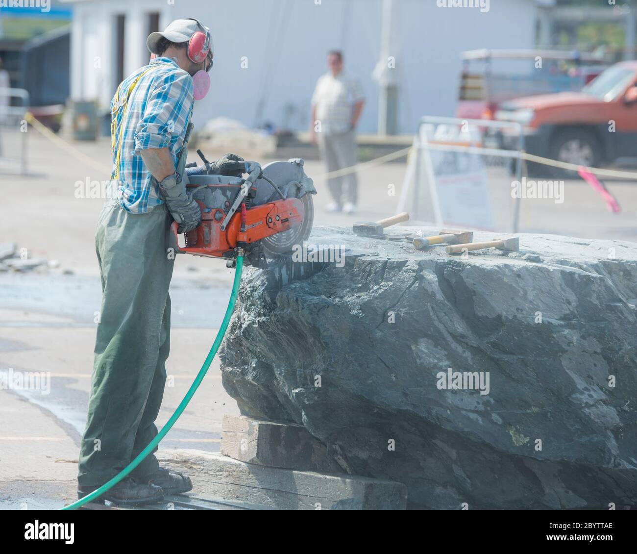 An artist works on a large block of stone at Sculpture Saint John, a ...