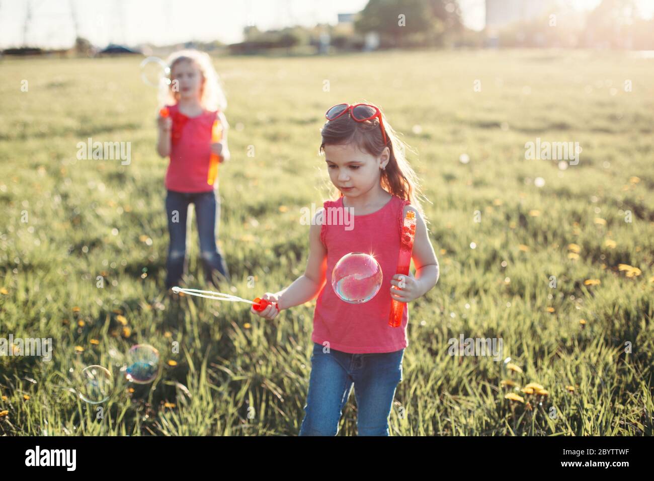 Catch a bubble. Girls friends blowing soap bubbles in park on summer ...