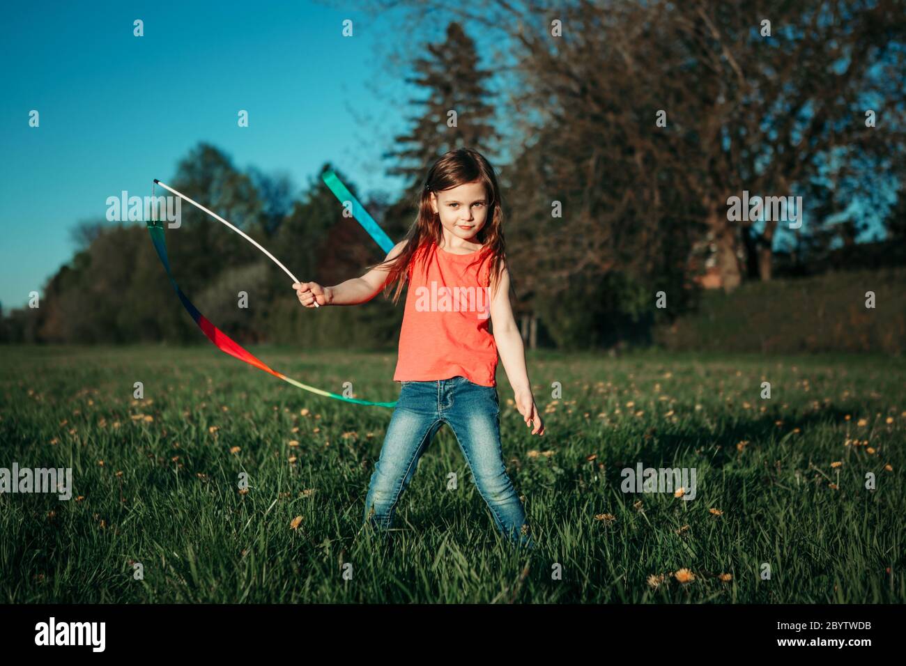 Happy child girl playing with ribbons in park. Cute adorable kid ...