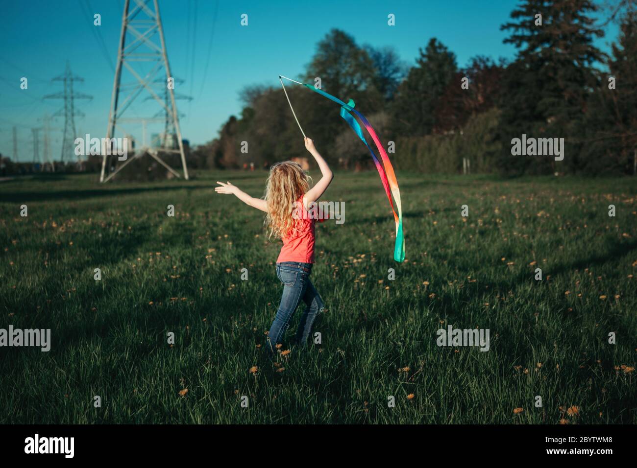 Happy child girl playing with ribbons in park. Cute adorable kid ...