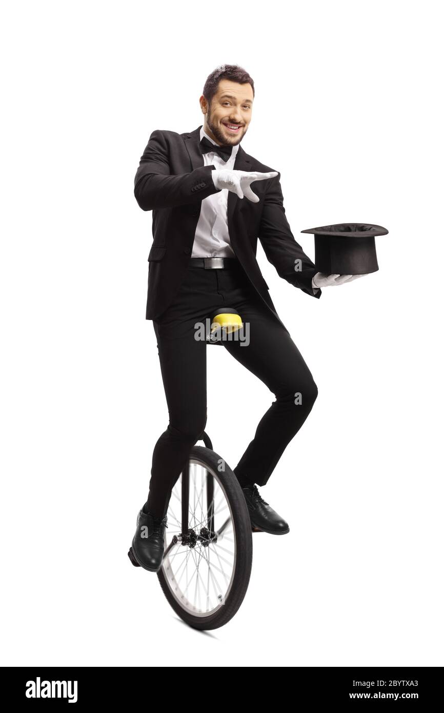 Magician riding a mono-cycle and performing a magic trick with a hat ...