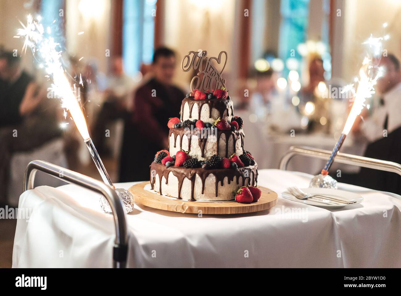 Three-tiered wedding cake with dripped chocolate and berries standing ...