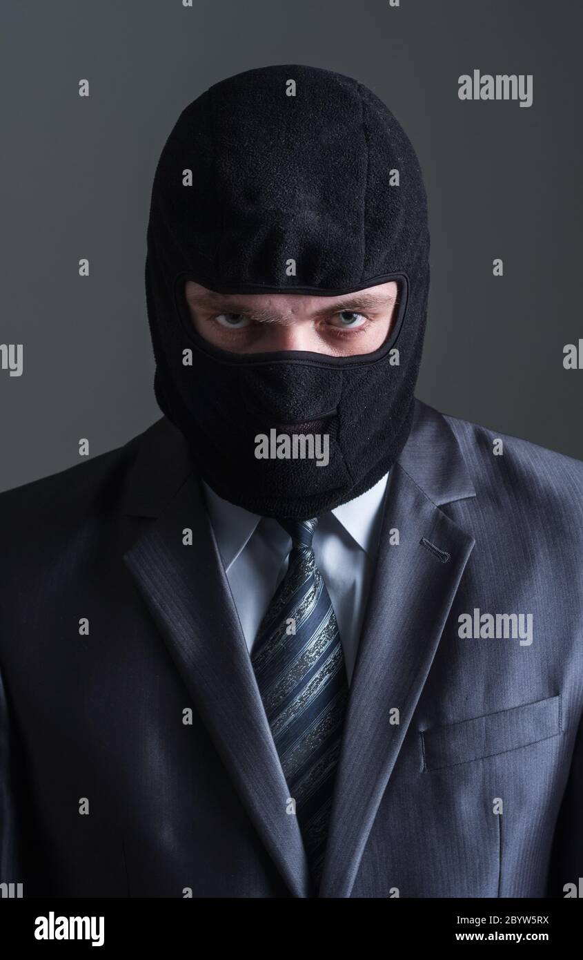 Thief in black mask and in office suit over grey Stock Photo - Alamy