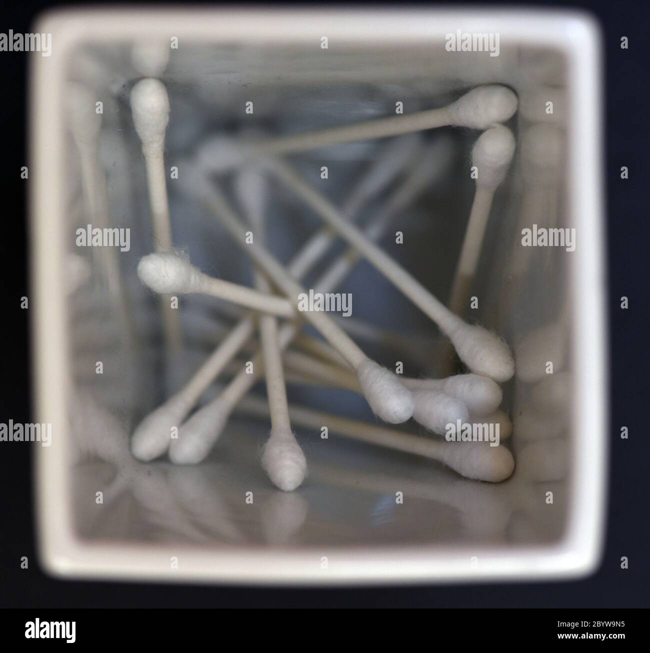 Overhead view of Q-Tip brand cotton swabs in a square ceramic container ...