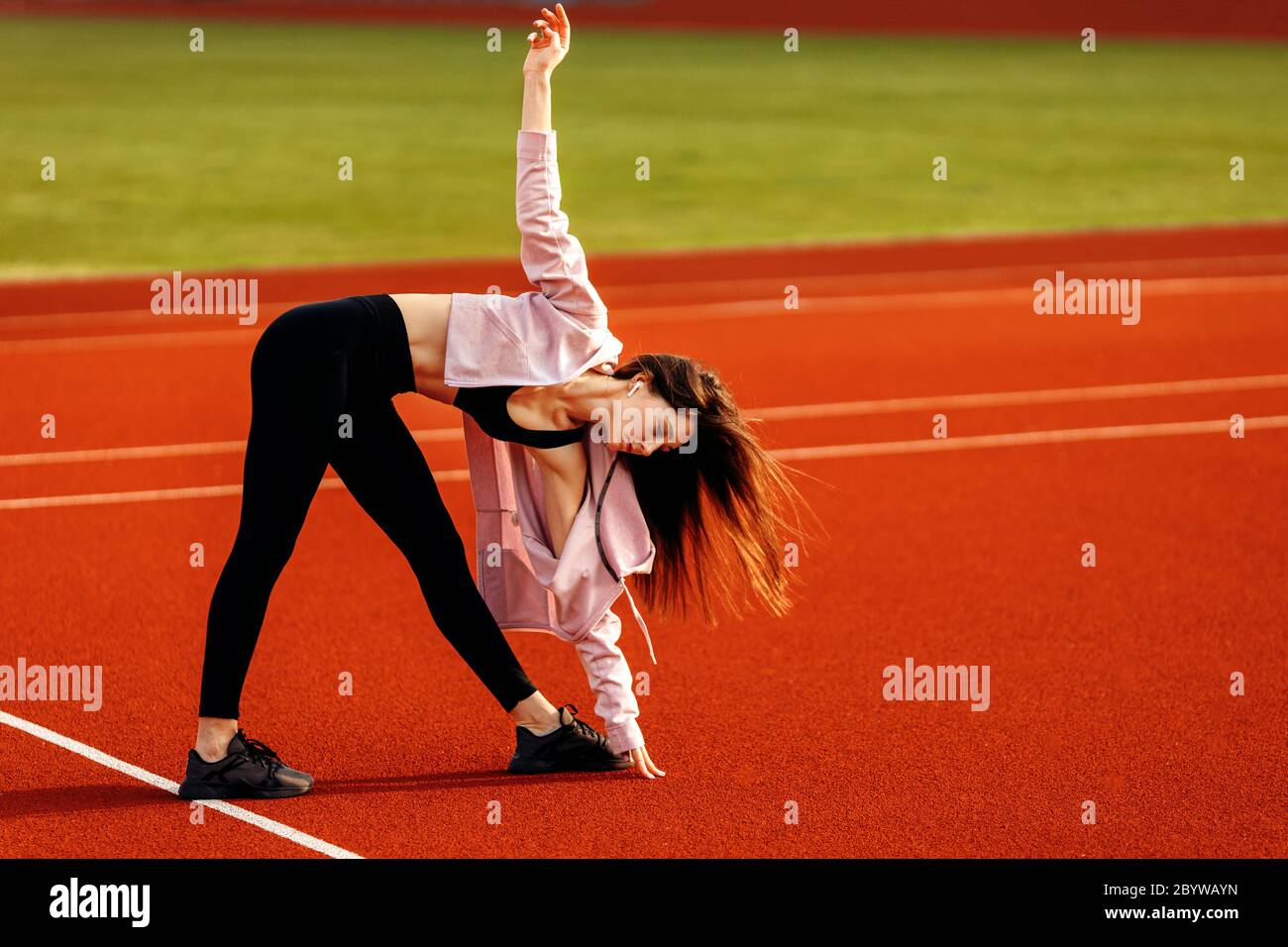 Fitness woman doing exercises before running on the stadium Stock Photo ...
