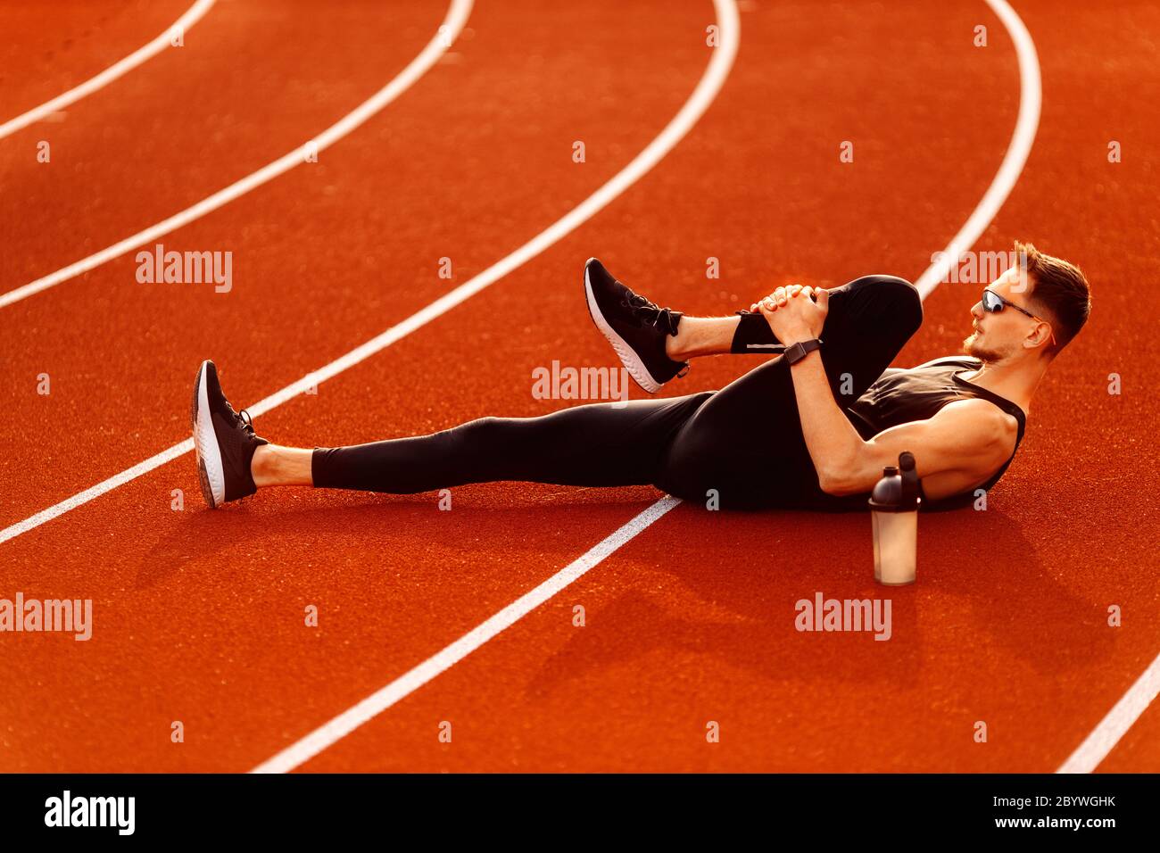 Young athlete resting after running in the stadium Stock Photo - Alamy