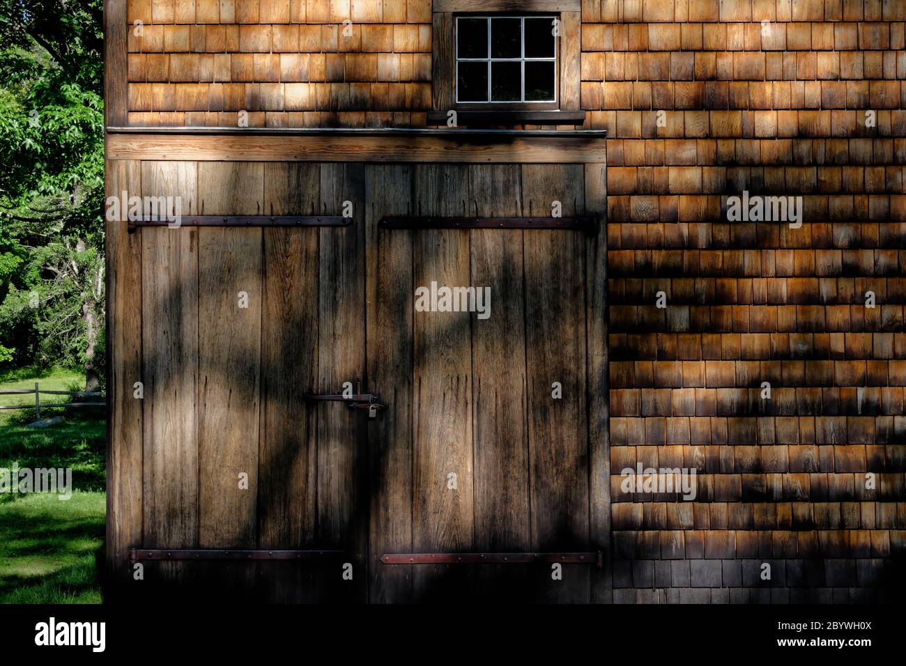 An 18th-century wood shingled barn with sliding door illuminated by the ...