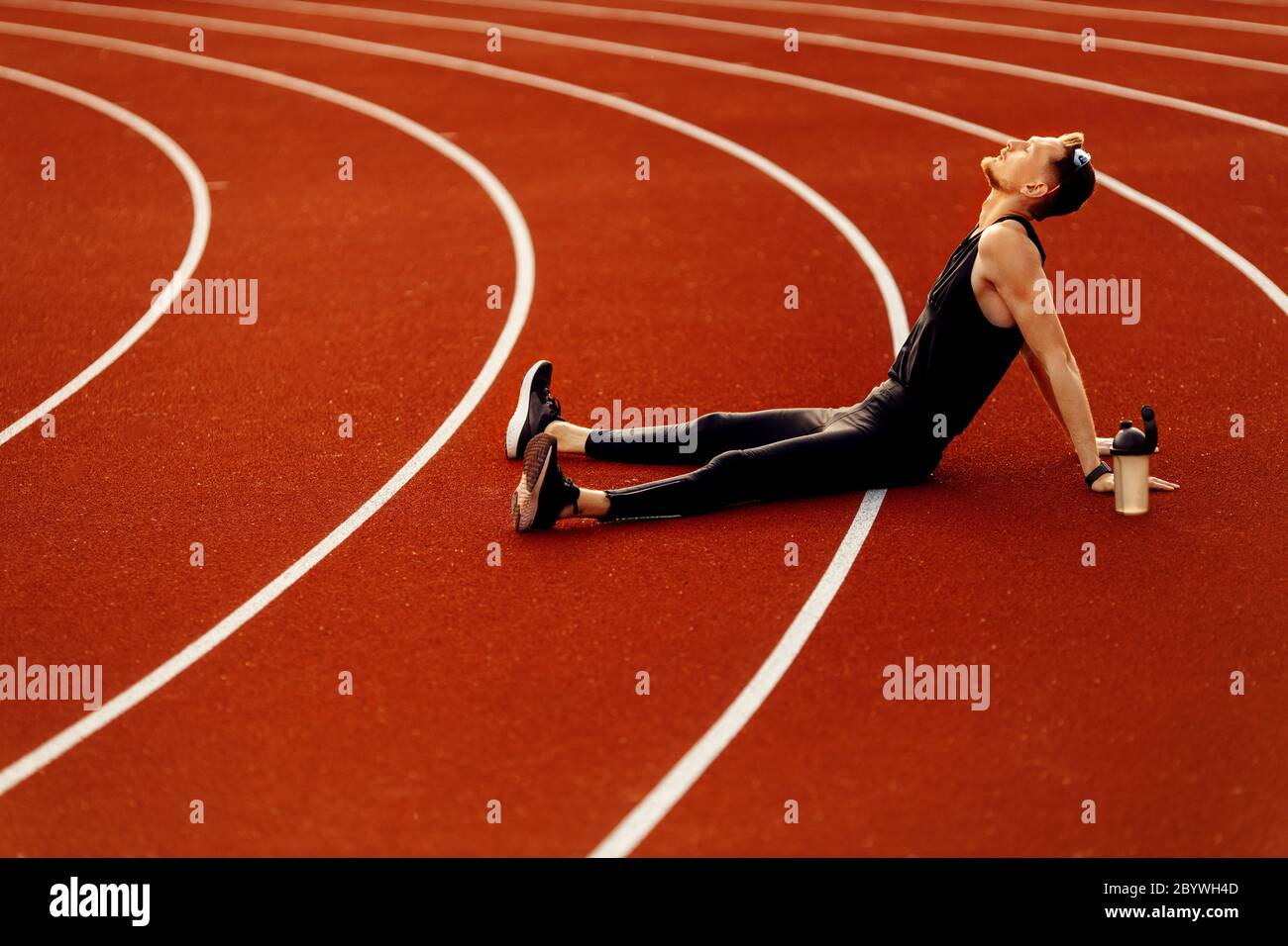Young athlete resting after running in the stadium Stock Photo - Alamy