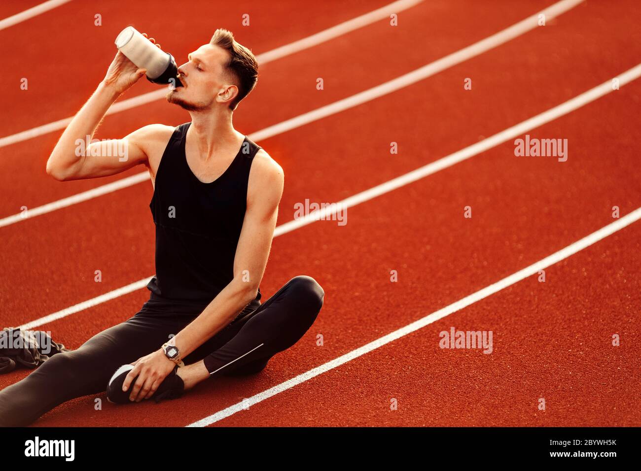 Young athlete resting after running in the stadium Stock Photo - Alamy
