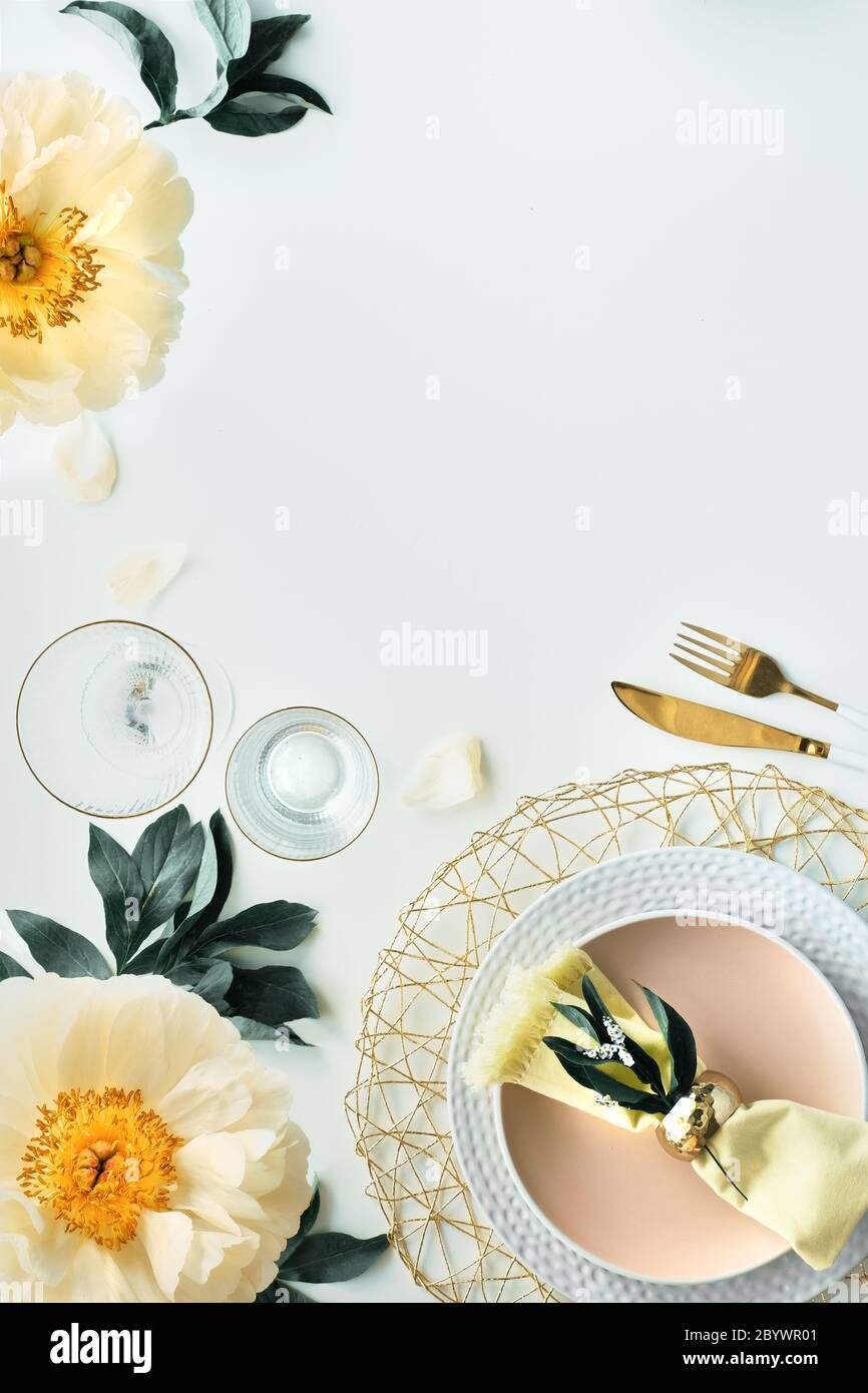 Contemporary table setting with peony flowers and golden utensils on ...
