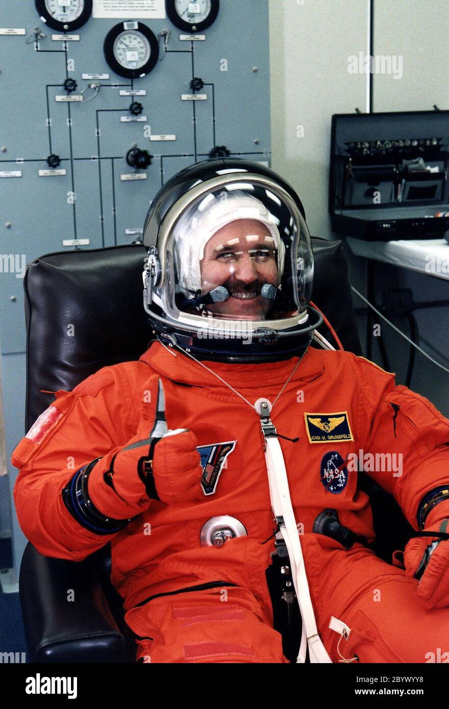 STS-81 Mission Specialist John M. Grunsfeld. gives a thumbs-up as he ...