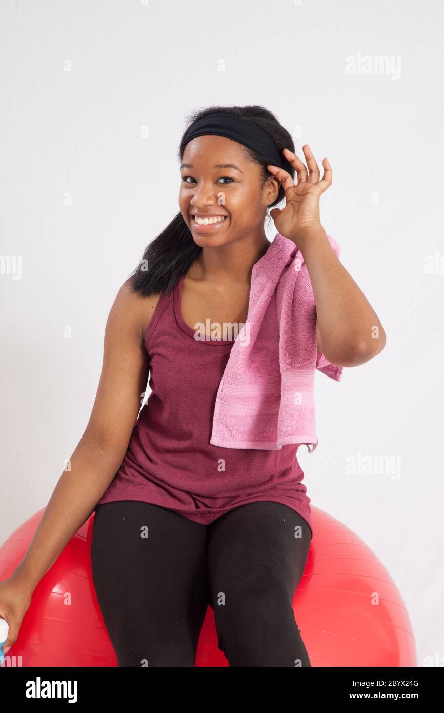 Lovely black woman sitting on a red exercise ball Stock Photo - Alamy