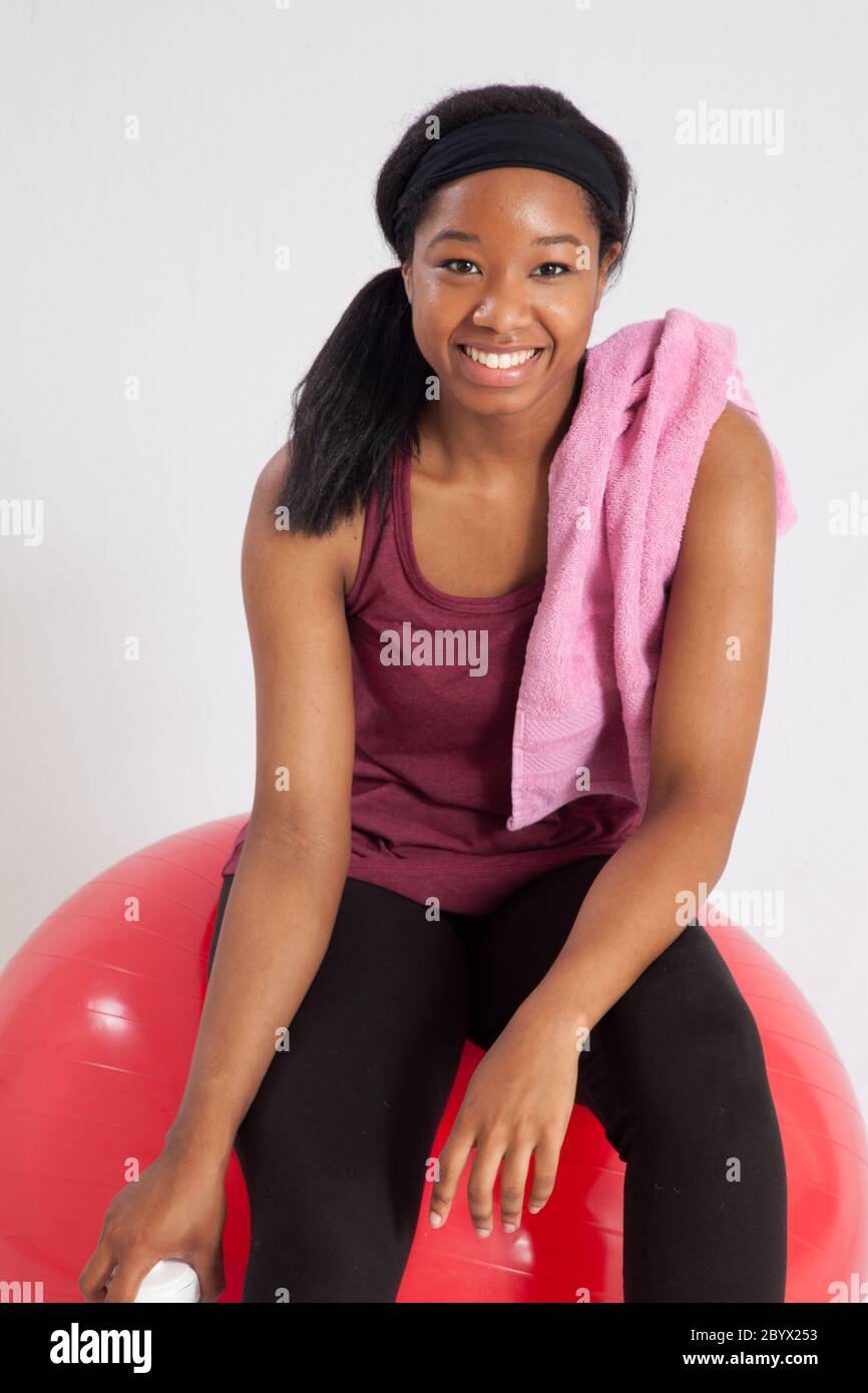 Lovely black woman sitting on a red exercise ball Stock Photo - Alamy