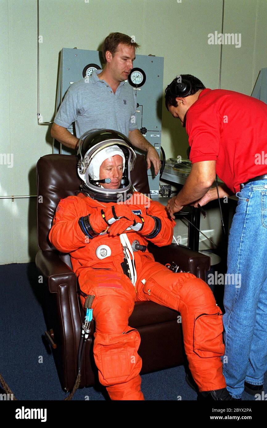 STS-87 Pilot Steven Lindsey dons his launch and entry suit with the help of two assistants in ...