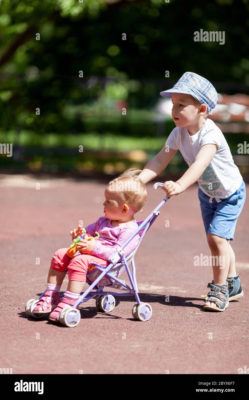 Boy pushing sister in a stroller Stock Photo - Alamy