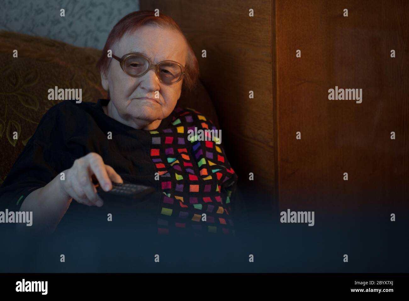 Old woman at home watching TV and changing channels Stock Photo - Alamy