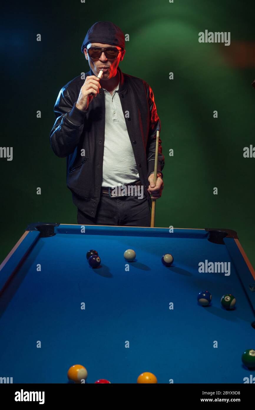 Trendy pool player in a leather jacket and cap Stock Photo - Alamy